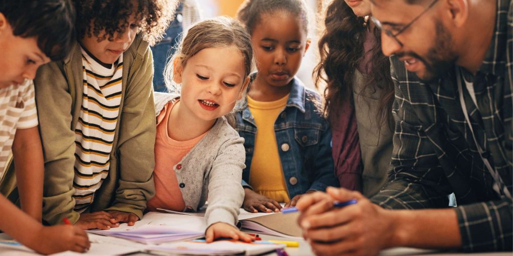 teacher working with children at desk
