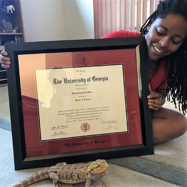 grad holding her UNGA diploma frame